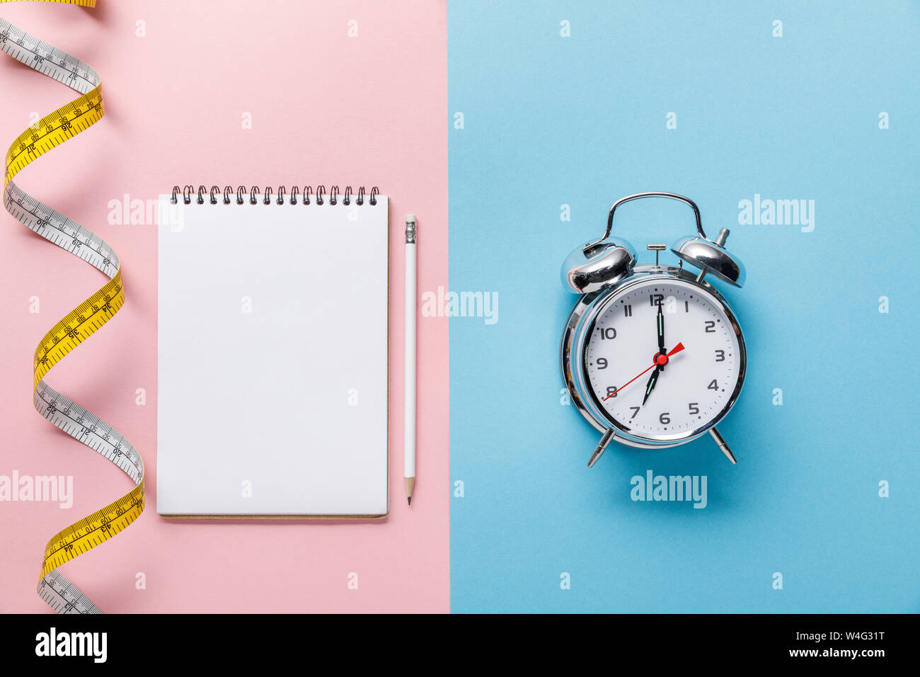 top view of measuring tape and blank notebook with pencil on blue and ...