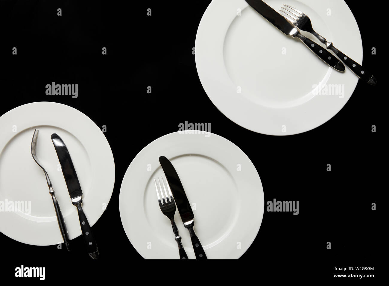 top view of white round plates with cutlery isolated on black Stock ...