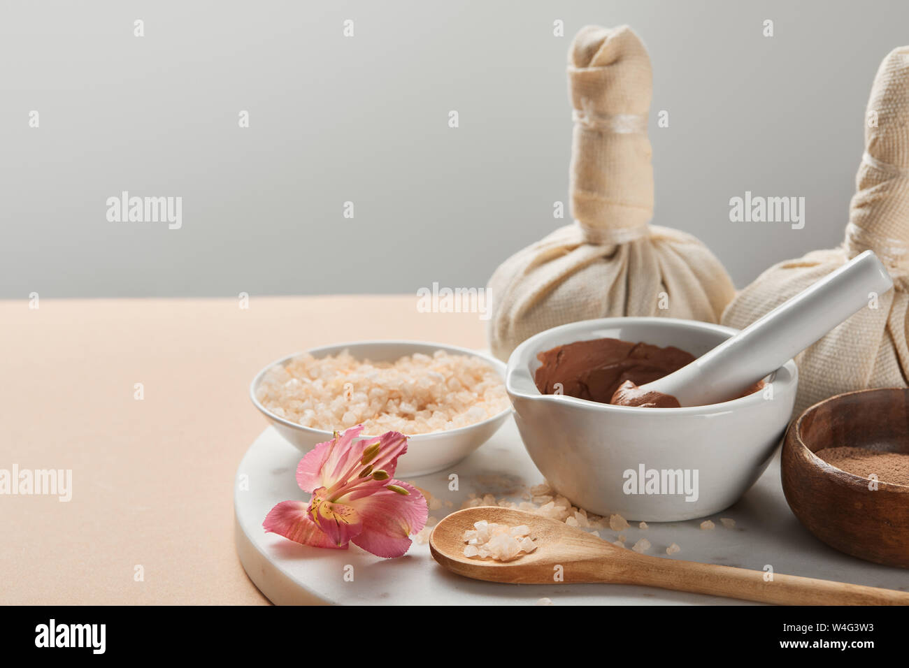 clay and sea salt in bowls on marble surface with flower and decora ...