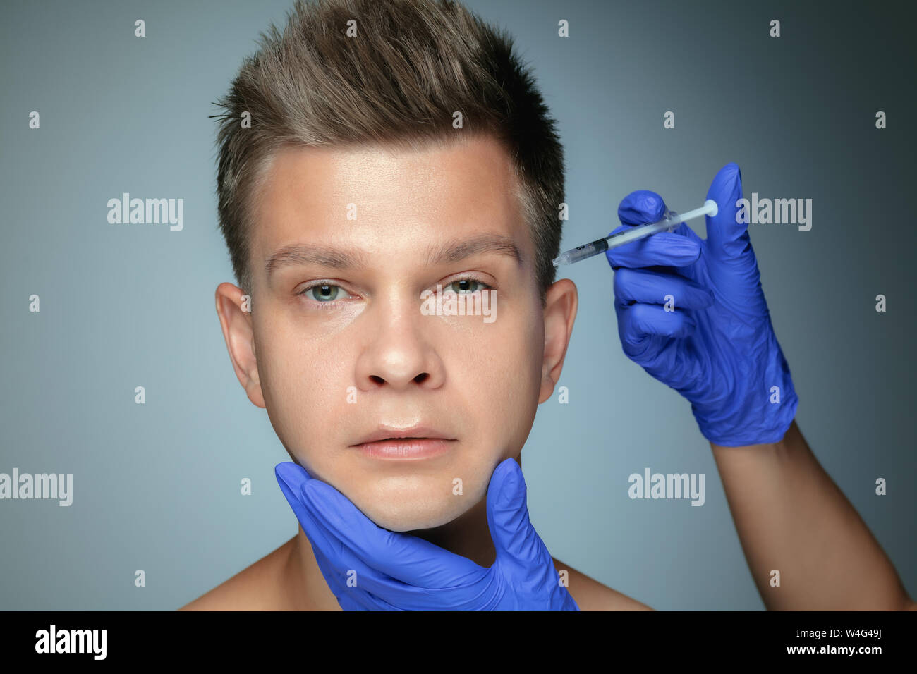 Close-up portrait of young man isolated on grey studio background ...