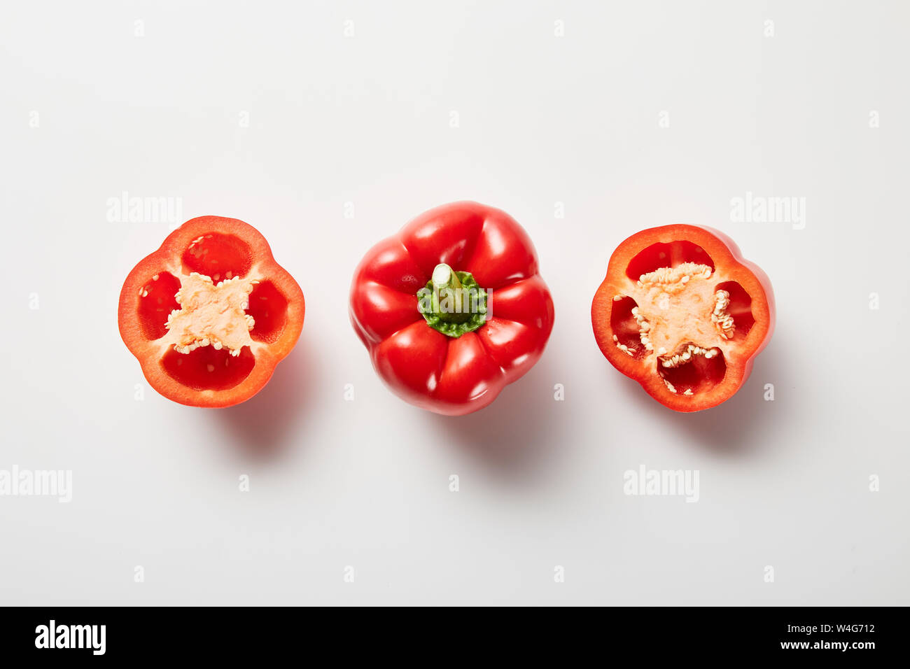 top view of red organic cut and whole bell peppers on white background ...