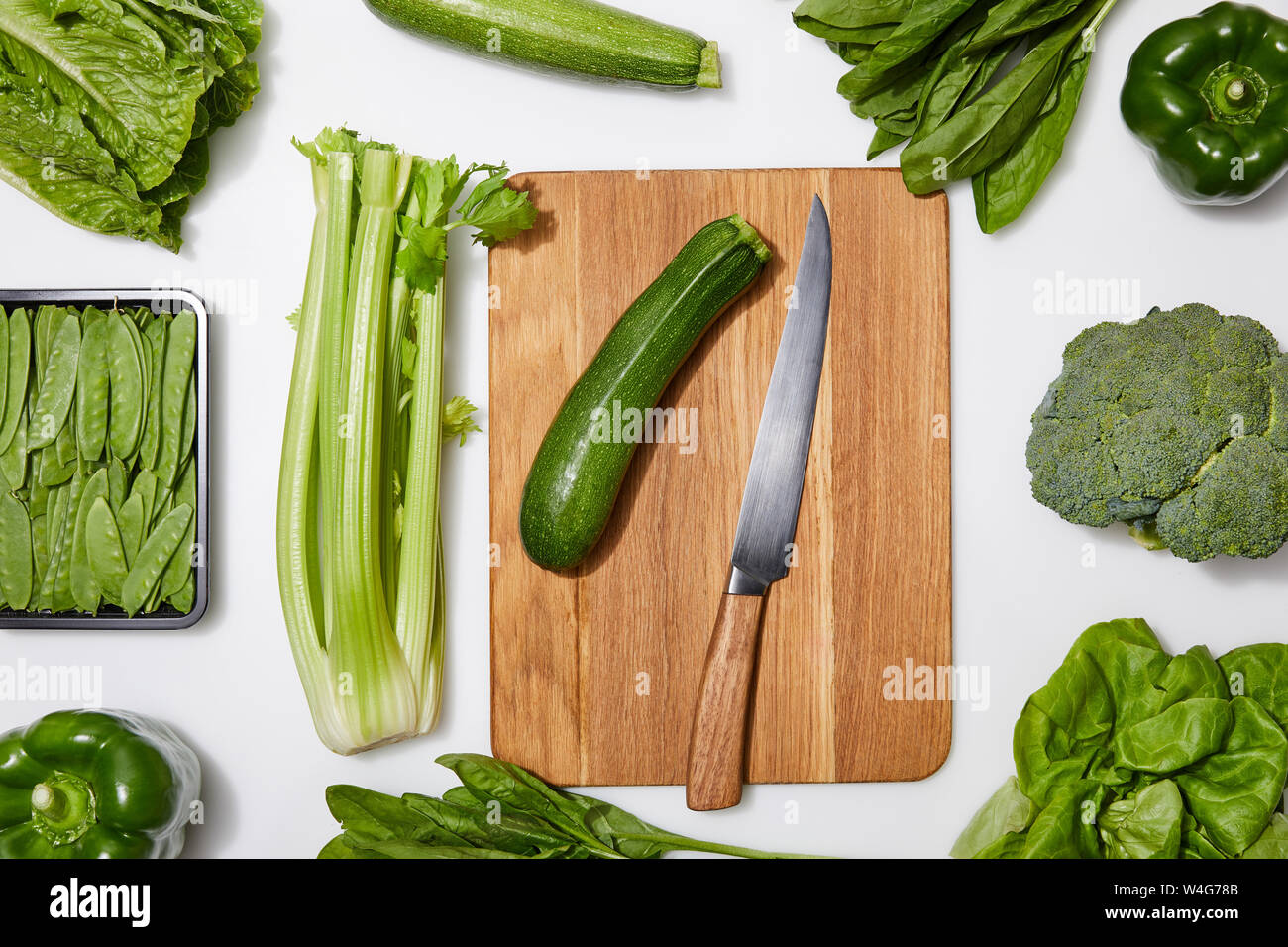 top view of green vegetables and wooden chopping board with knife on ...