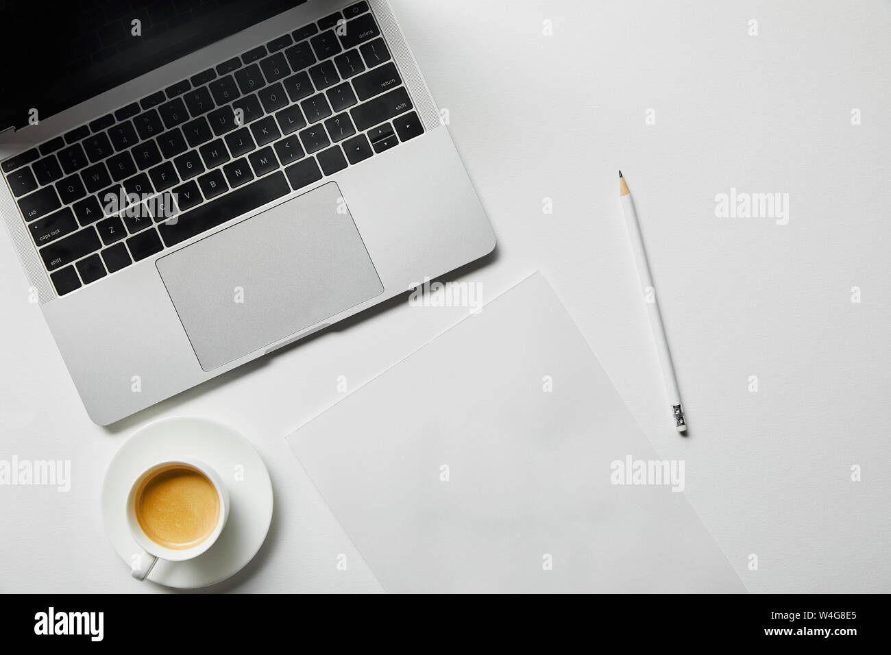 top view of laptop, coffee, paper and pencil on white surface Stock ...