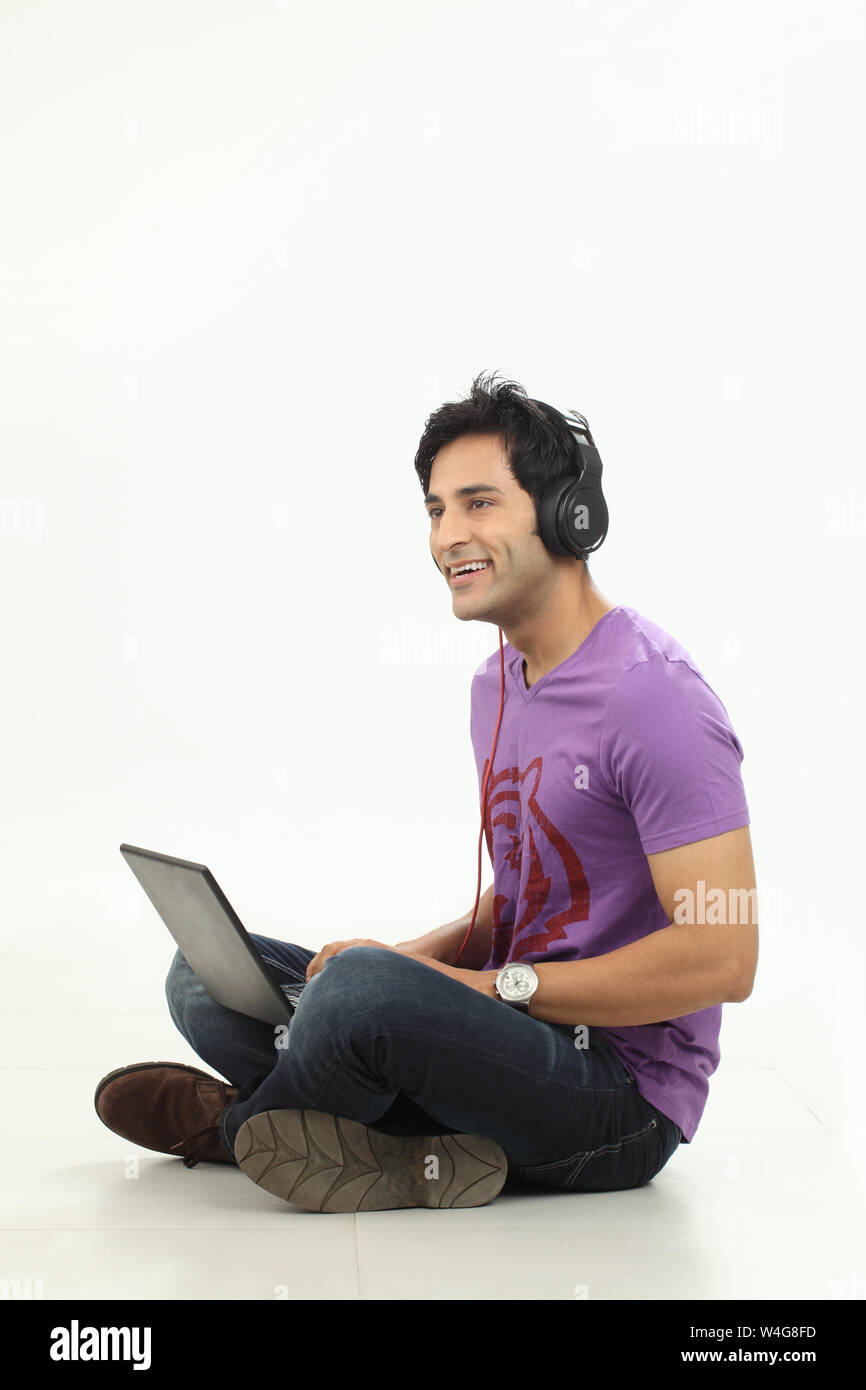 Man wearing headphones and using a laptop Stock Photo - Alamy