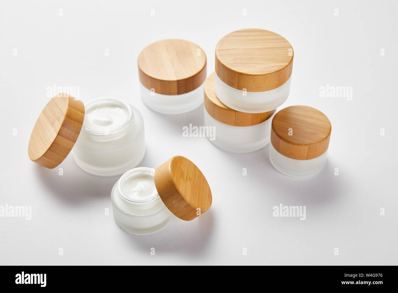 open and closed jars with face cream and wooden caps on white Stock ...