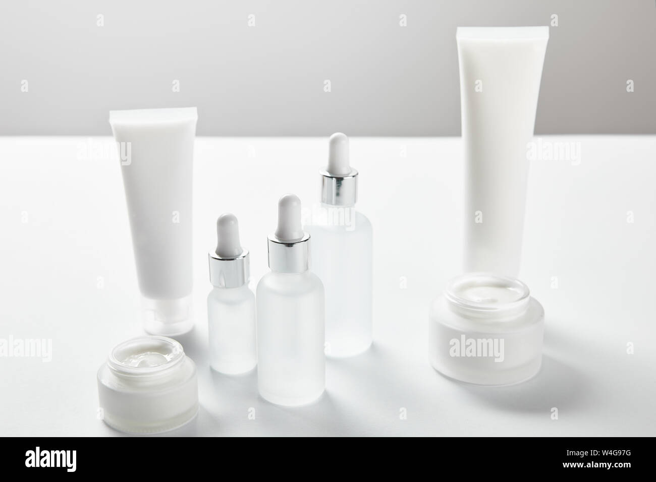 cream tubes, cosmetic glass bottles and open jars with cream on white ...