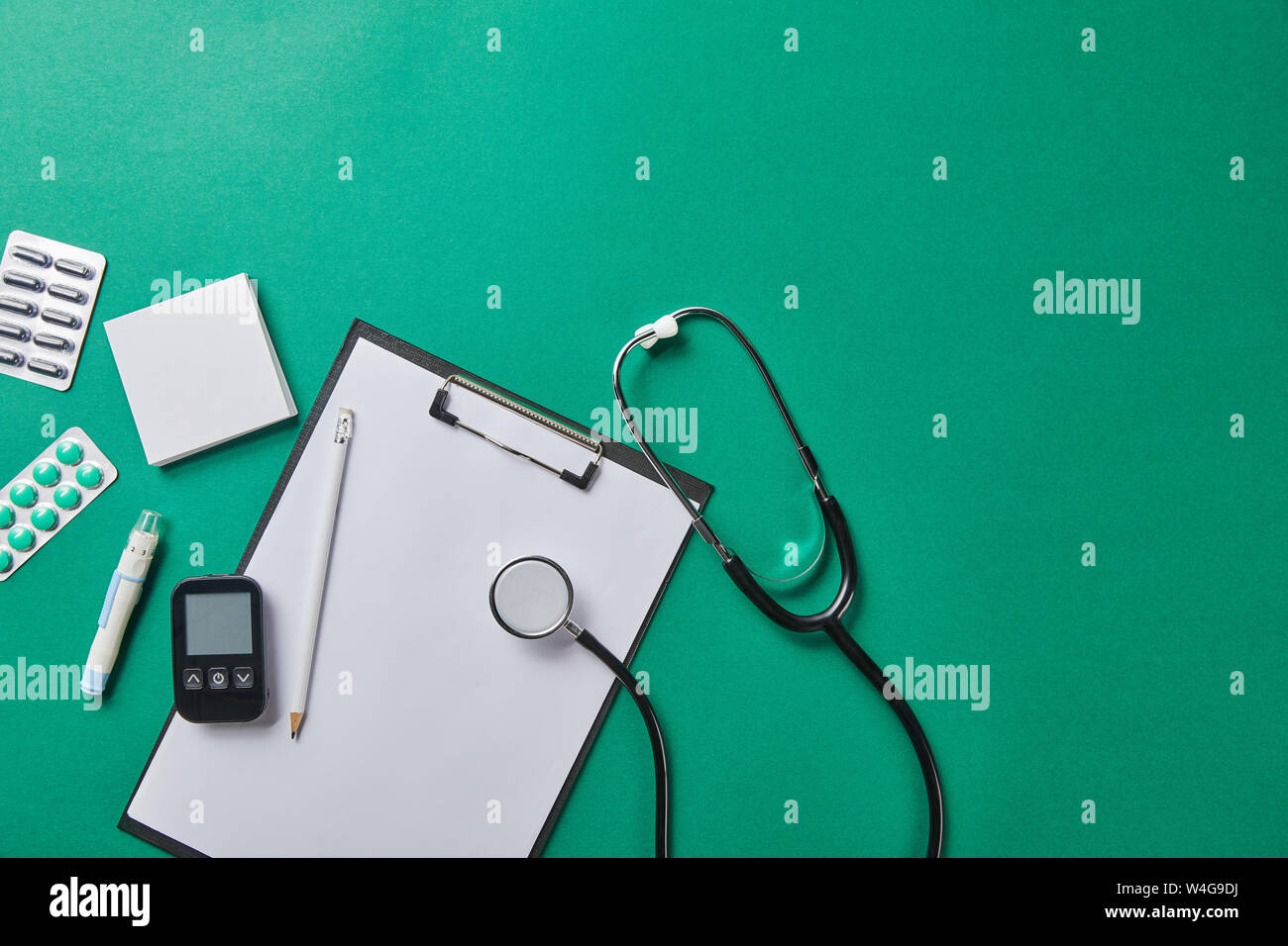 top view of blood lancet, sticky notes, blister packs and stethoscope ...