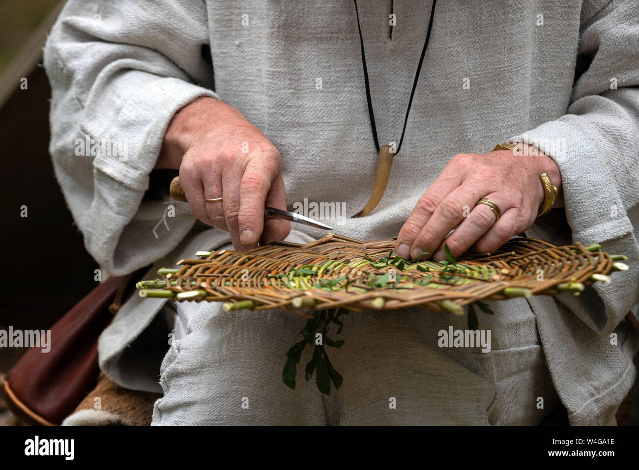 Close up of craftsman wearing rural clothes making wicker basket of ...