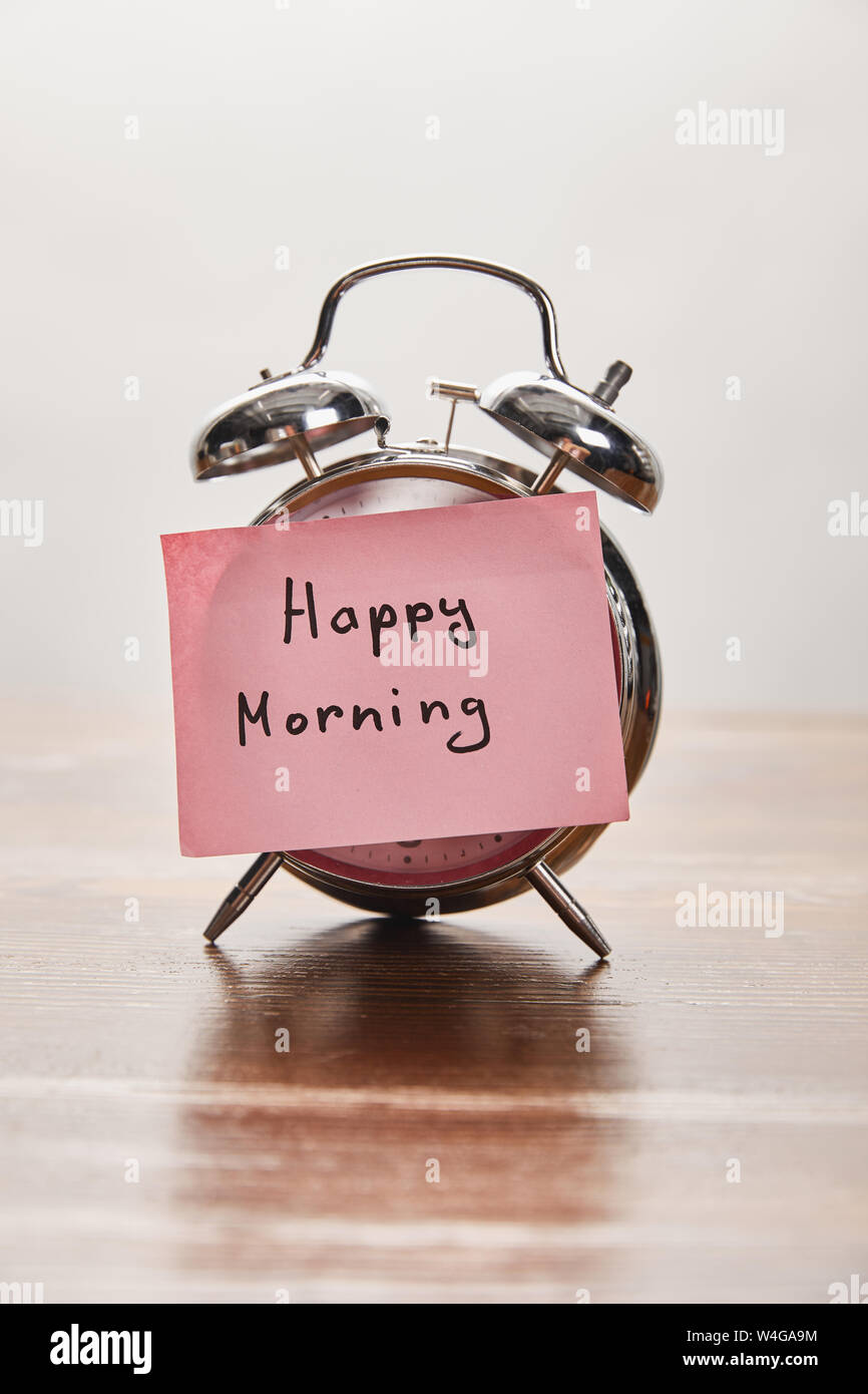 silver alarm clock with happy morning lettering on pink sticky note on ...