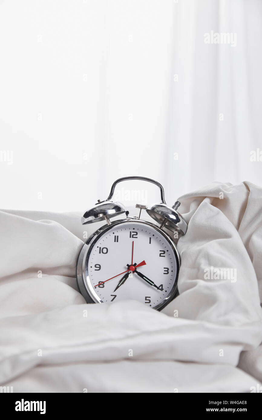 silver alarm clock in blanket in white bed Stock Photo - Alamy