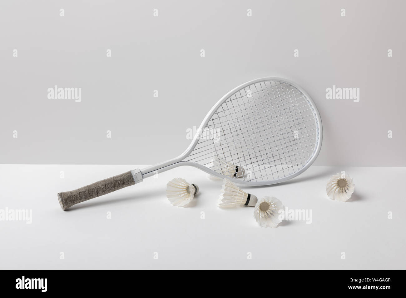 white badminton shuttlecocks near white racket on white background ...