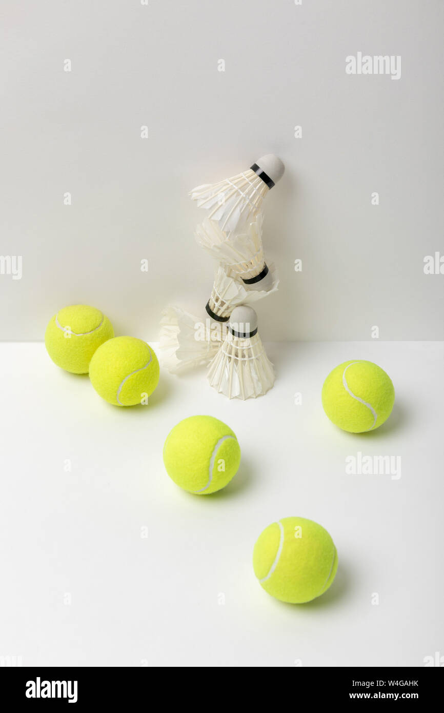 white badminton shuttlecocks and bright yellow tennis balls on white ...