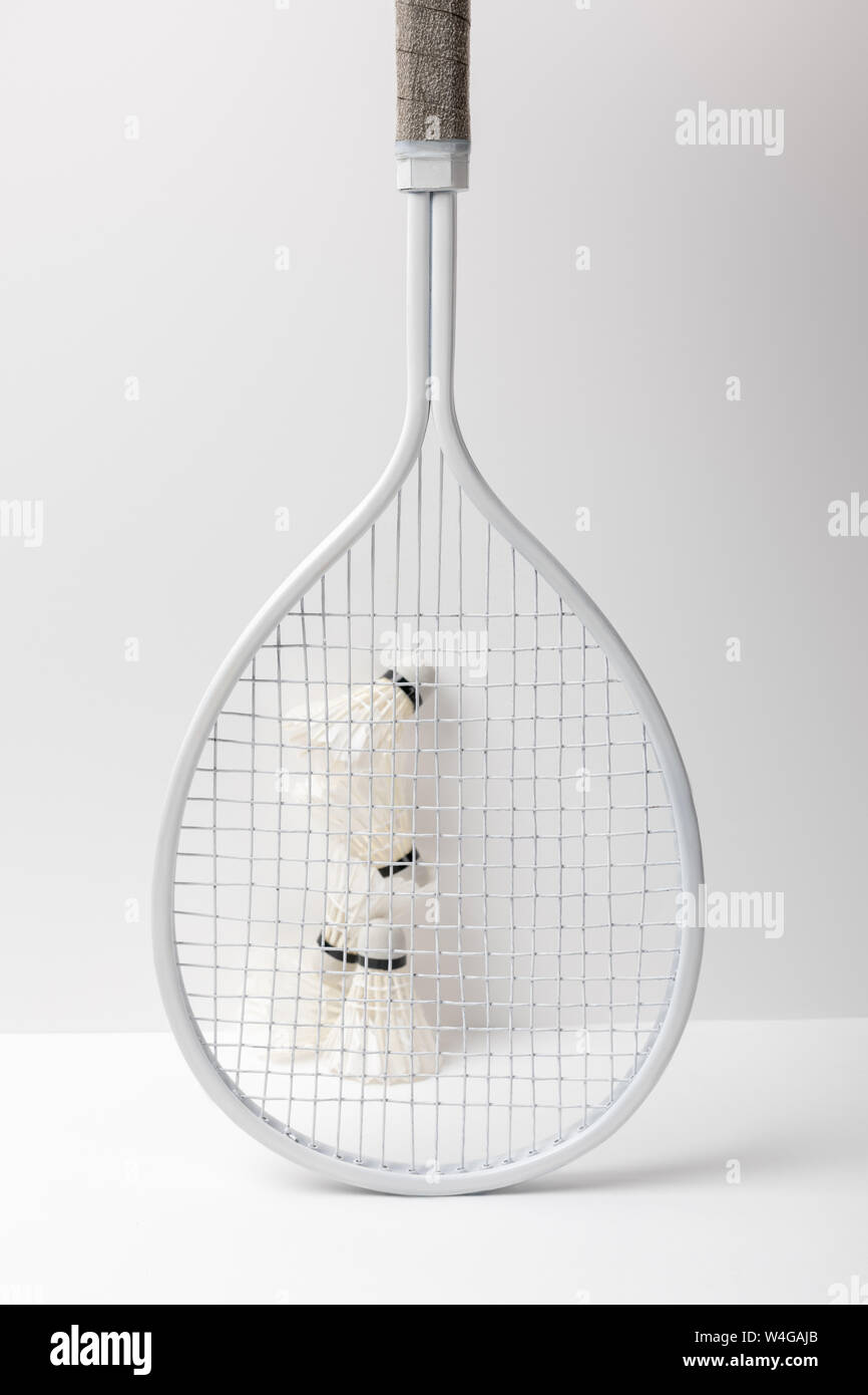 white badminton shuttlecocks behind white racket on white background ...