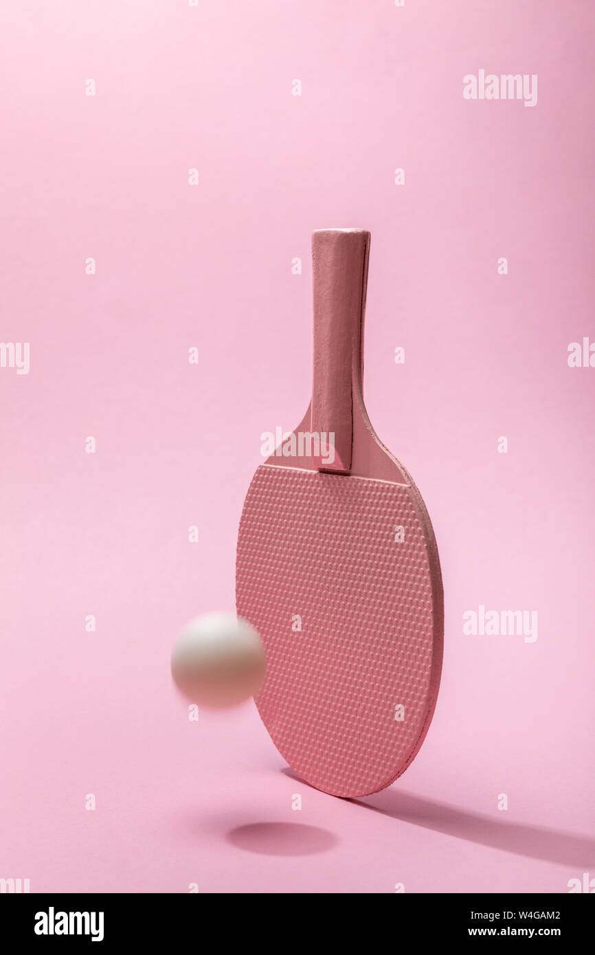 ping-pong racket and white flying ball on pink background with copy ...