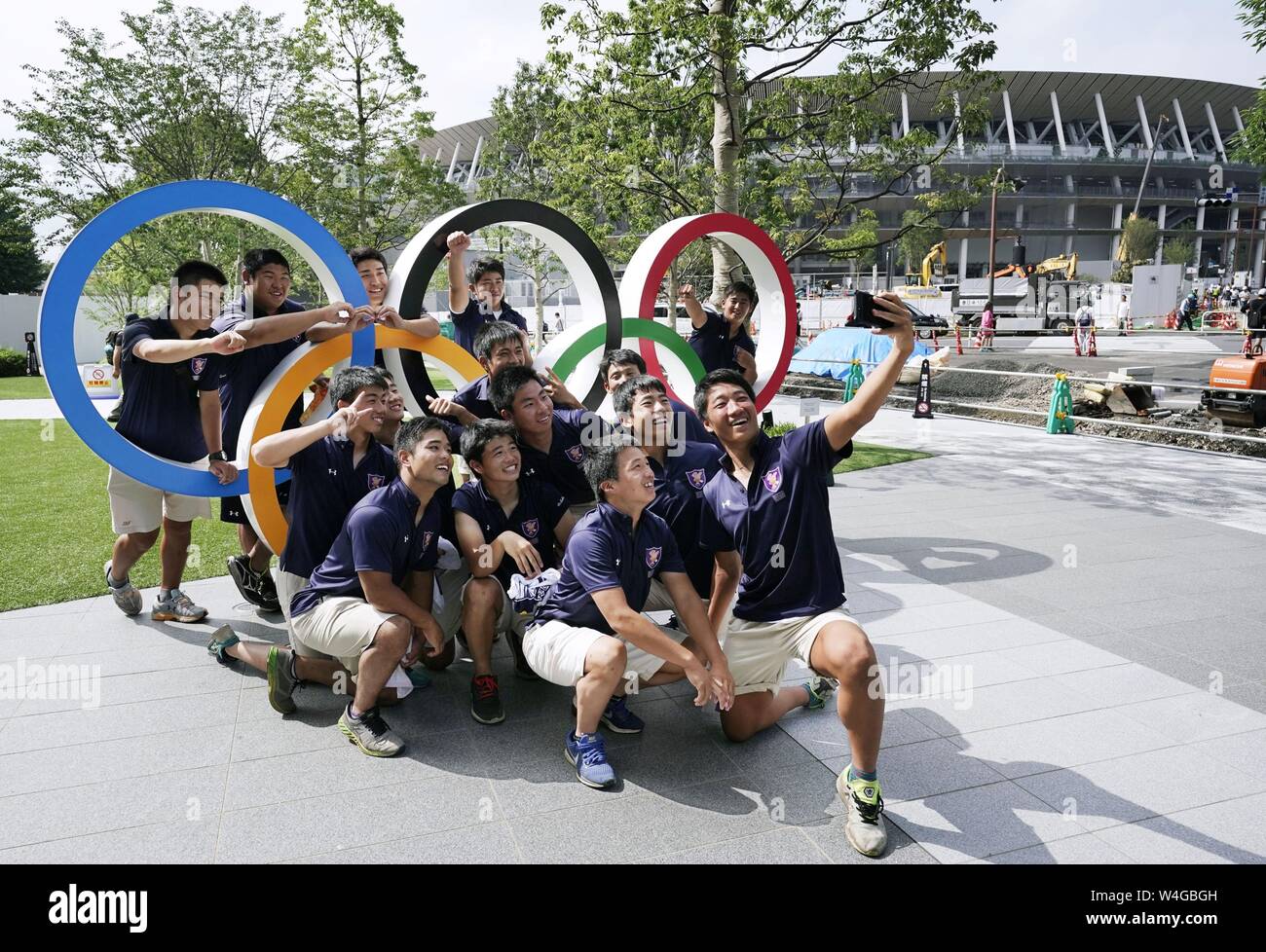 People pose at Olympic rings set up near New National Stadium in Tokyo ...