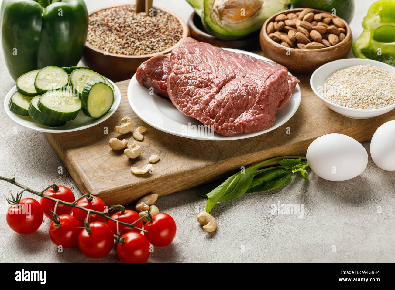 fresh raw meat on wooden chopping board near nuts, vegetables and ...