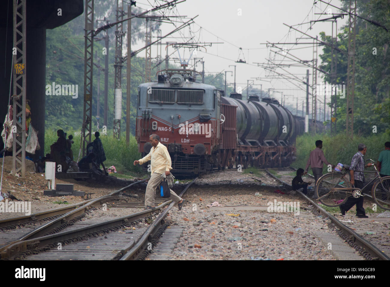 Group of people crossing railway tracks with train in background, Delhi ...