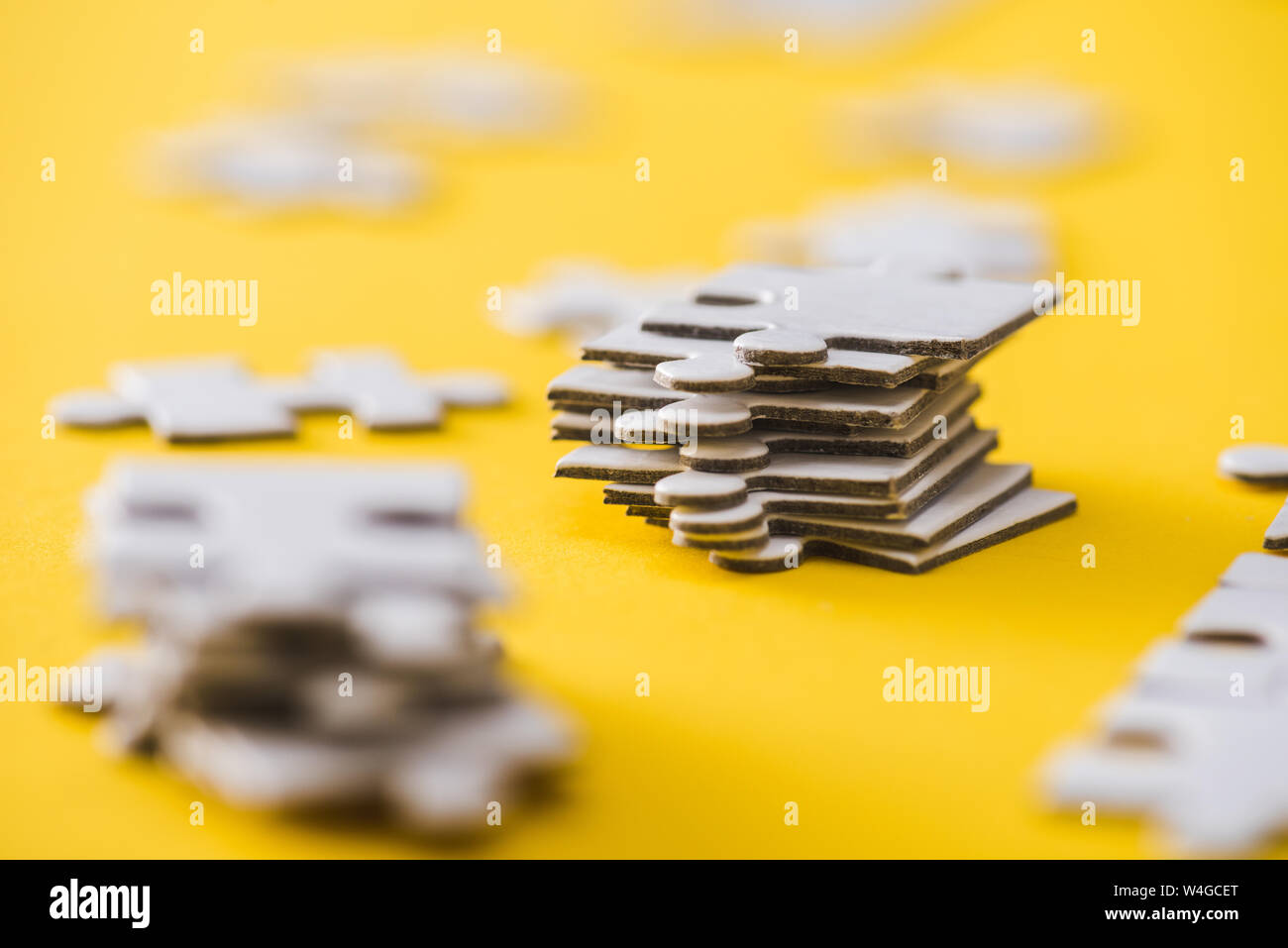 selective focus of stacked white puzzle pieces on yellow Stock Photo ...