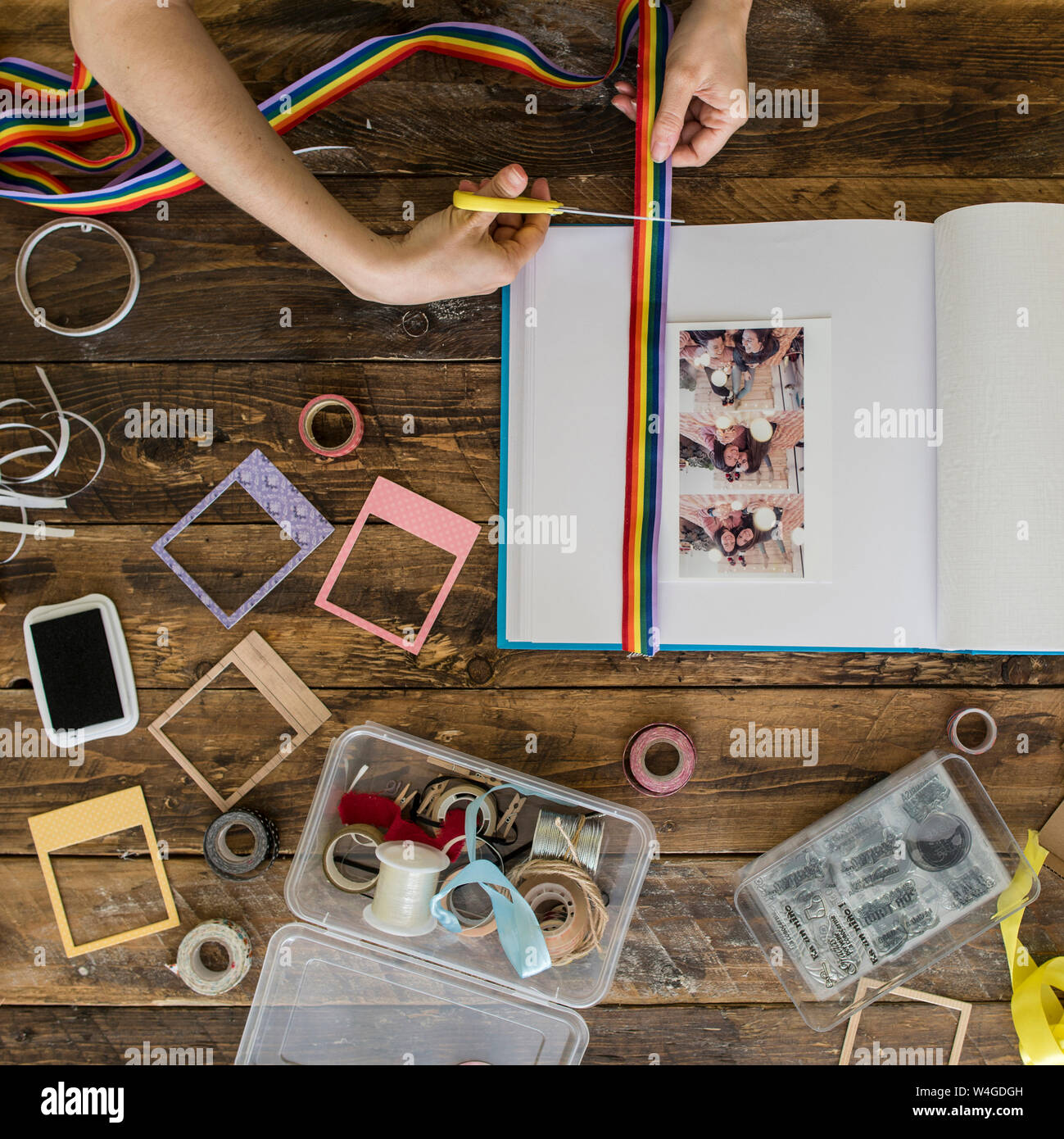 Top view of woman's hands decorating a photo album with a rainbow ...