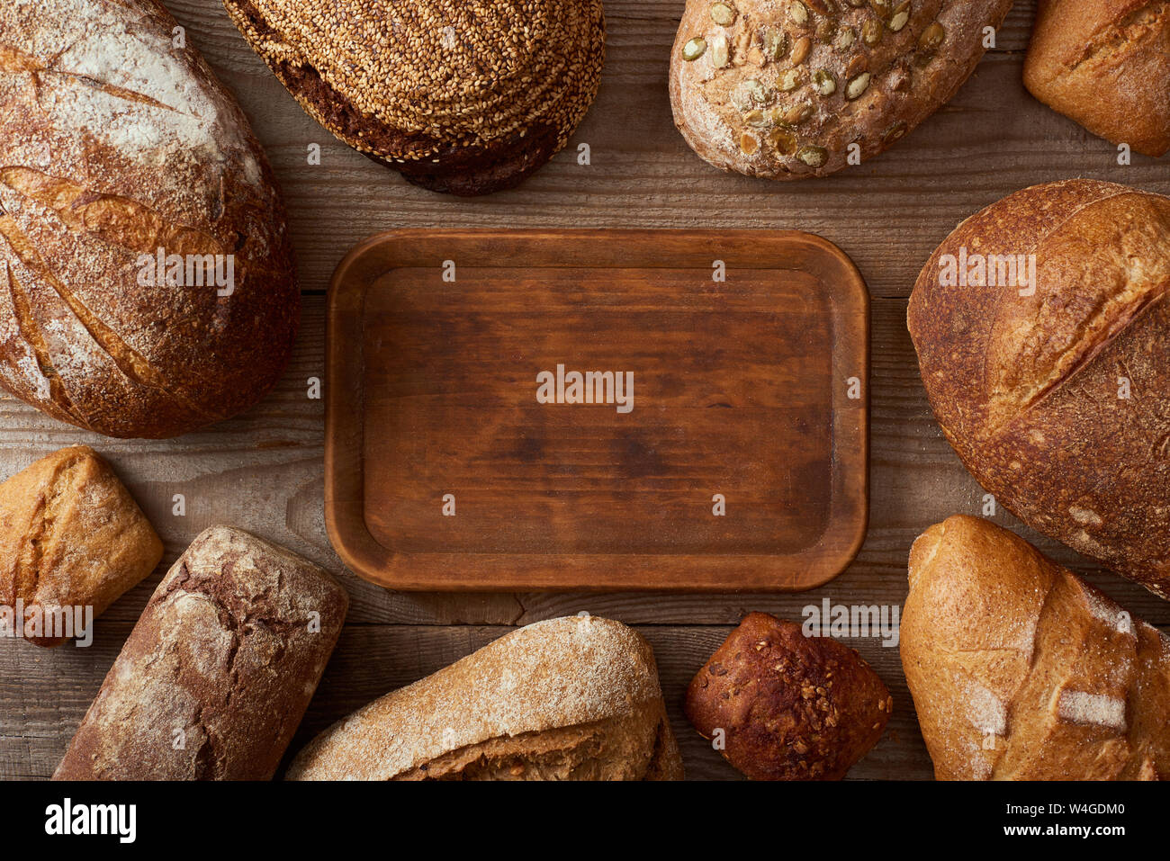 top view of fresh homemade loaves of bread around wooden empty chopping ...