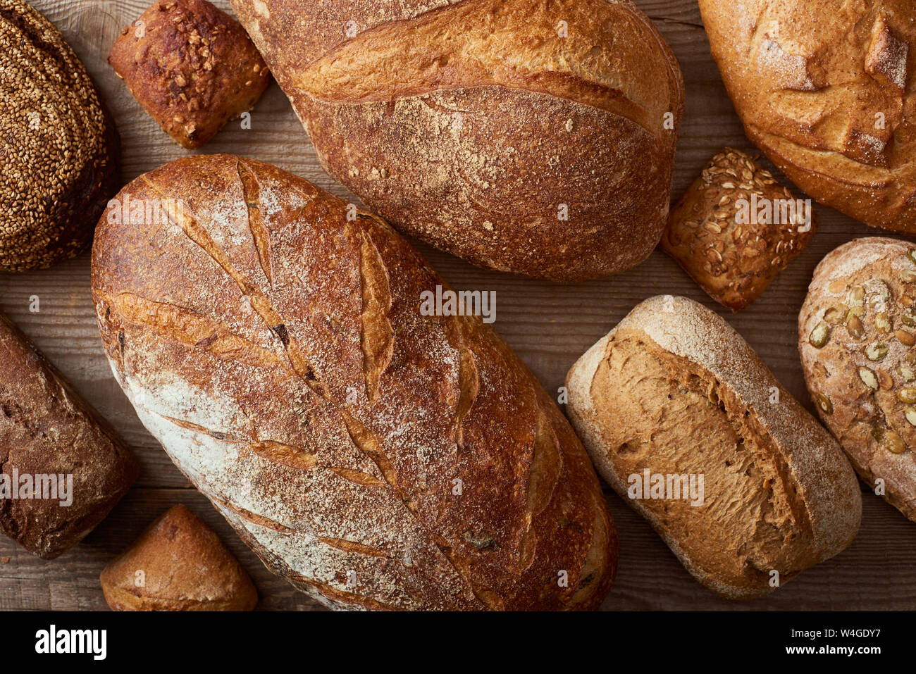 top view of fresh homemade loaves of bread and buns on wooden rustic ...