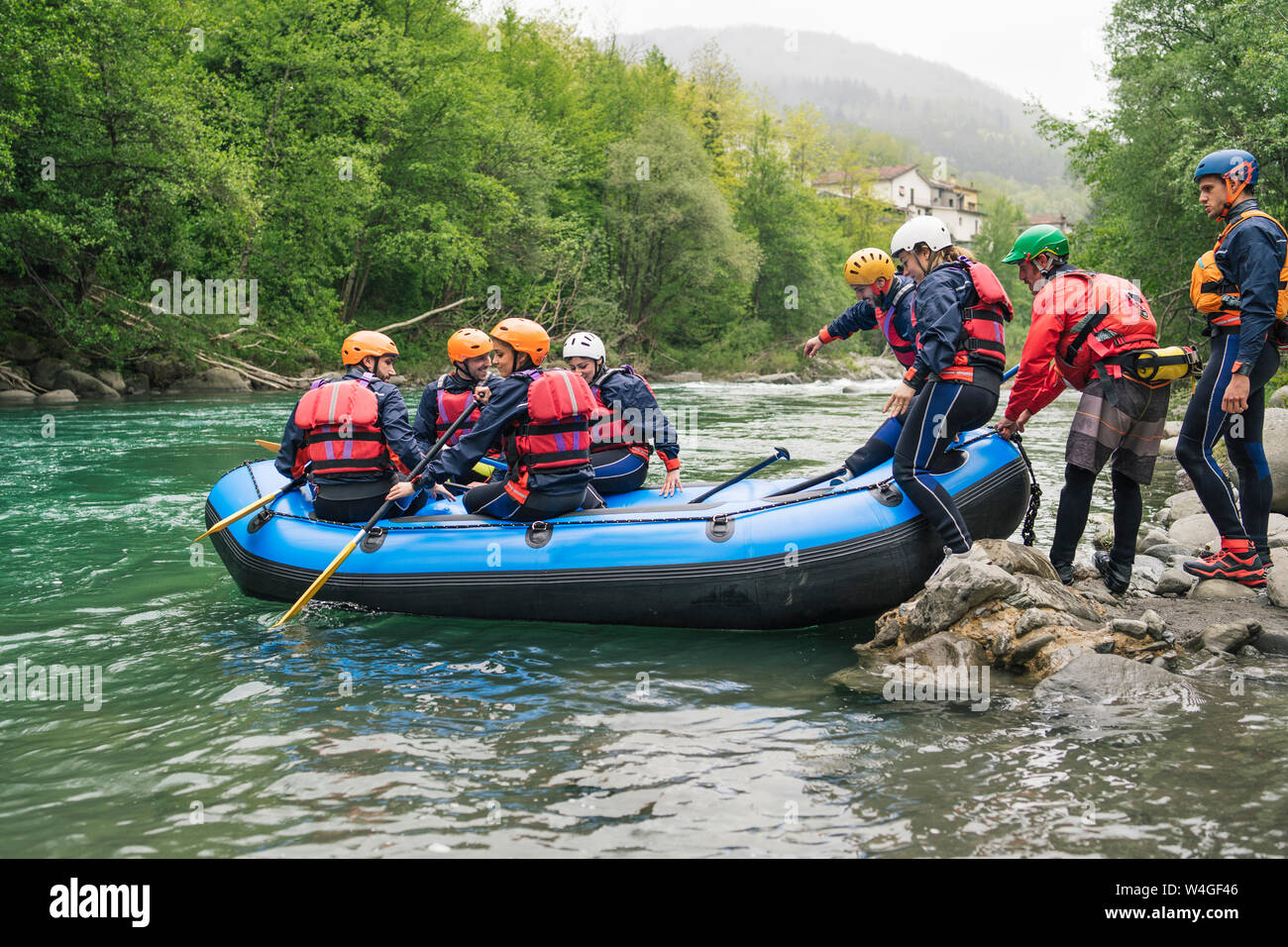 Group of people starting a rafting trip in rubber dinghy on a river ...