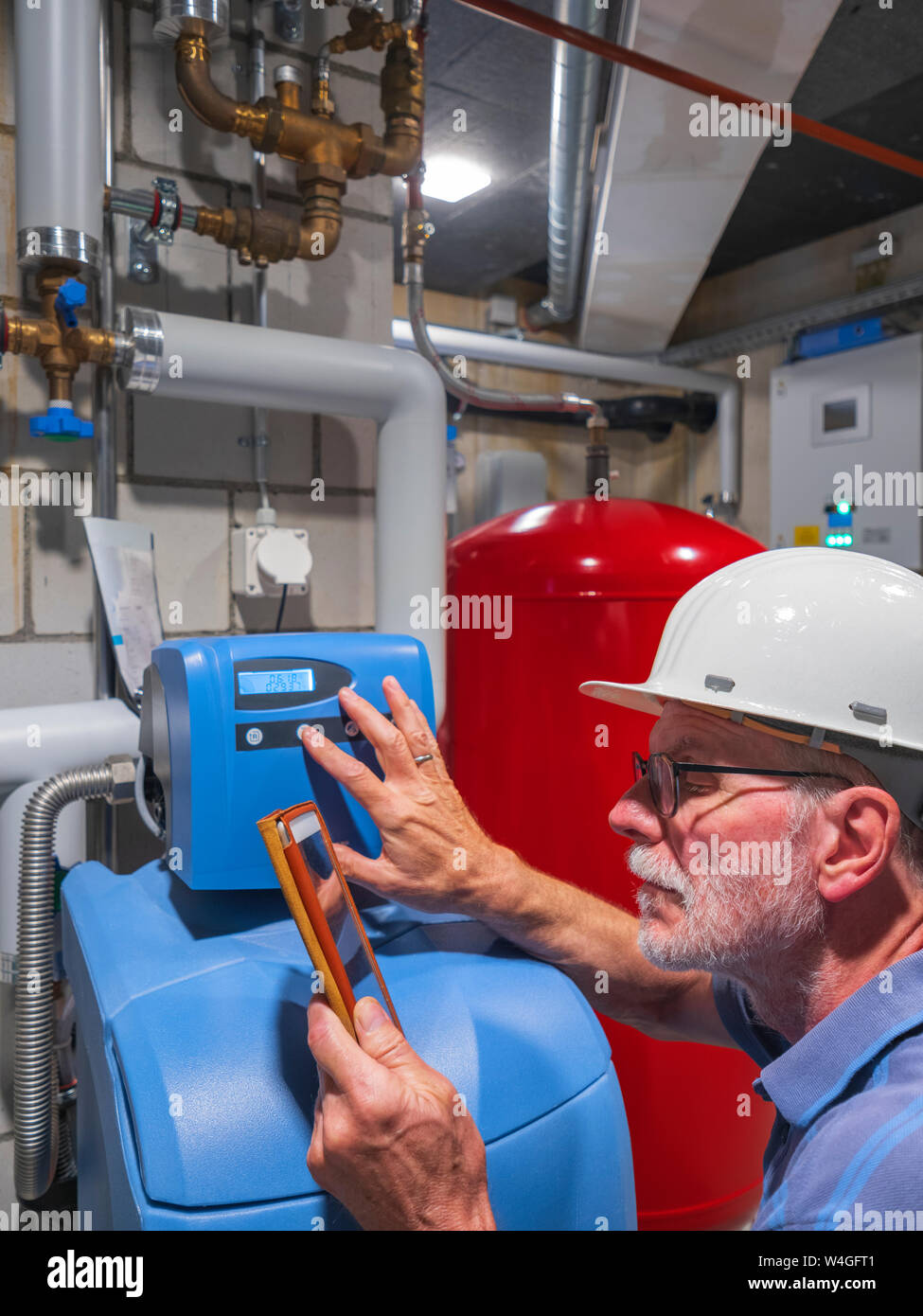 Senior craftsman checking water-processing unit, reading tablet Stock ...