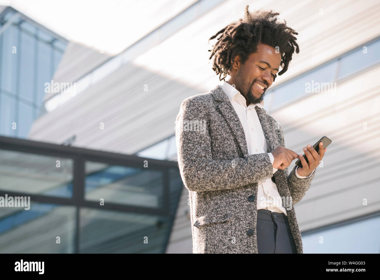 Smiling businessman using cell phone outside office Stock Photo - Alamy