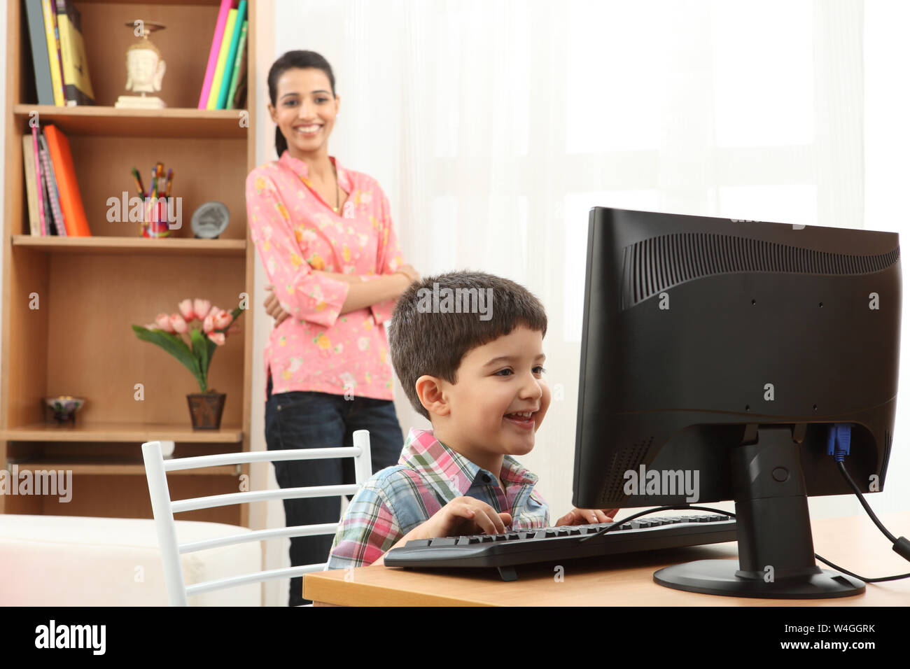 Indian boy working on a computer and mother watching him Stock Photo ...