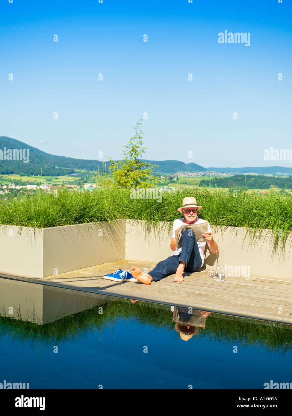 Senior man reading newspaper at swimming pool Stock Photo - Alamy