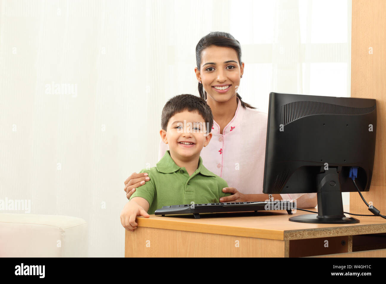 Boy smiling with his mother in front of a desktop pc Stock Photo - Alamy