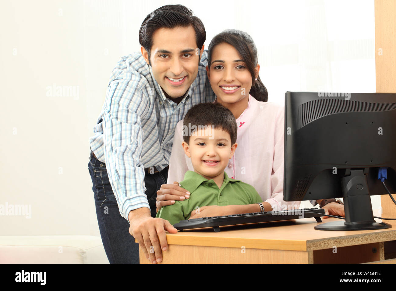 Family smiling in front of a desktop pc Stock Photo - Alamy