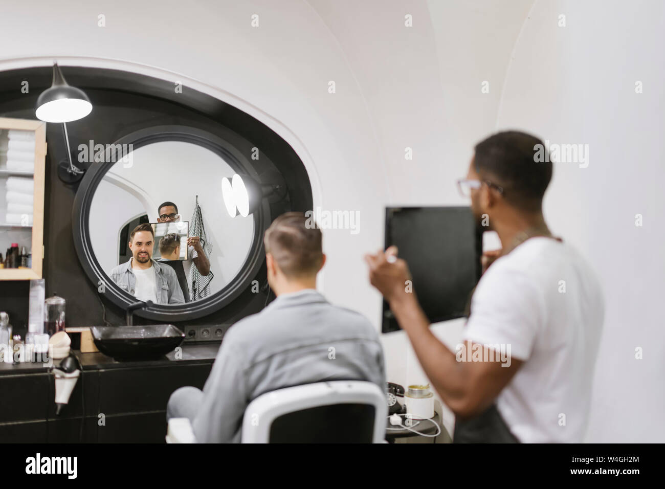 Barber showing man his haircut in mirror at barber shop Stock Photo - Alamy