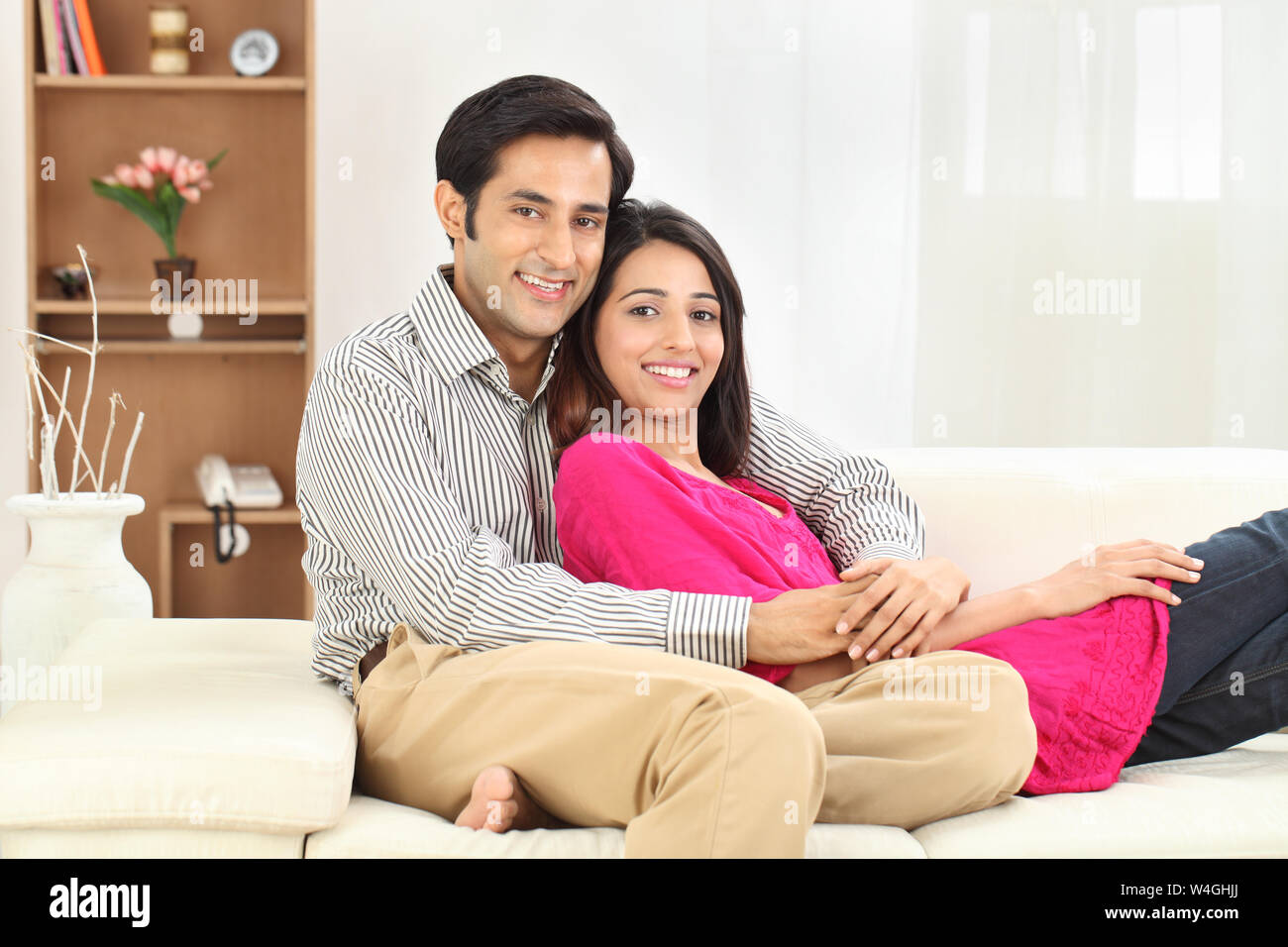 Couple sitting on a couch and smiling Stock Photo - Alamy