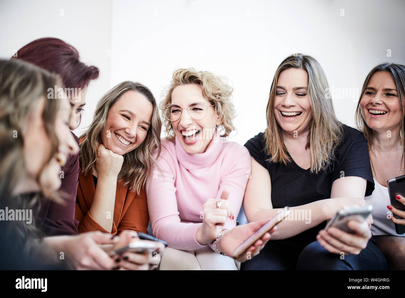Group of six laughing women with smartphones Stock Photo - Alamy