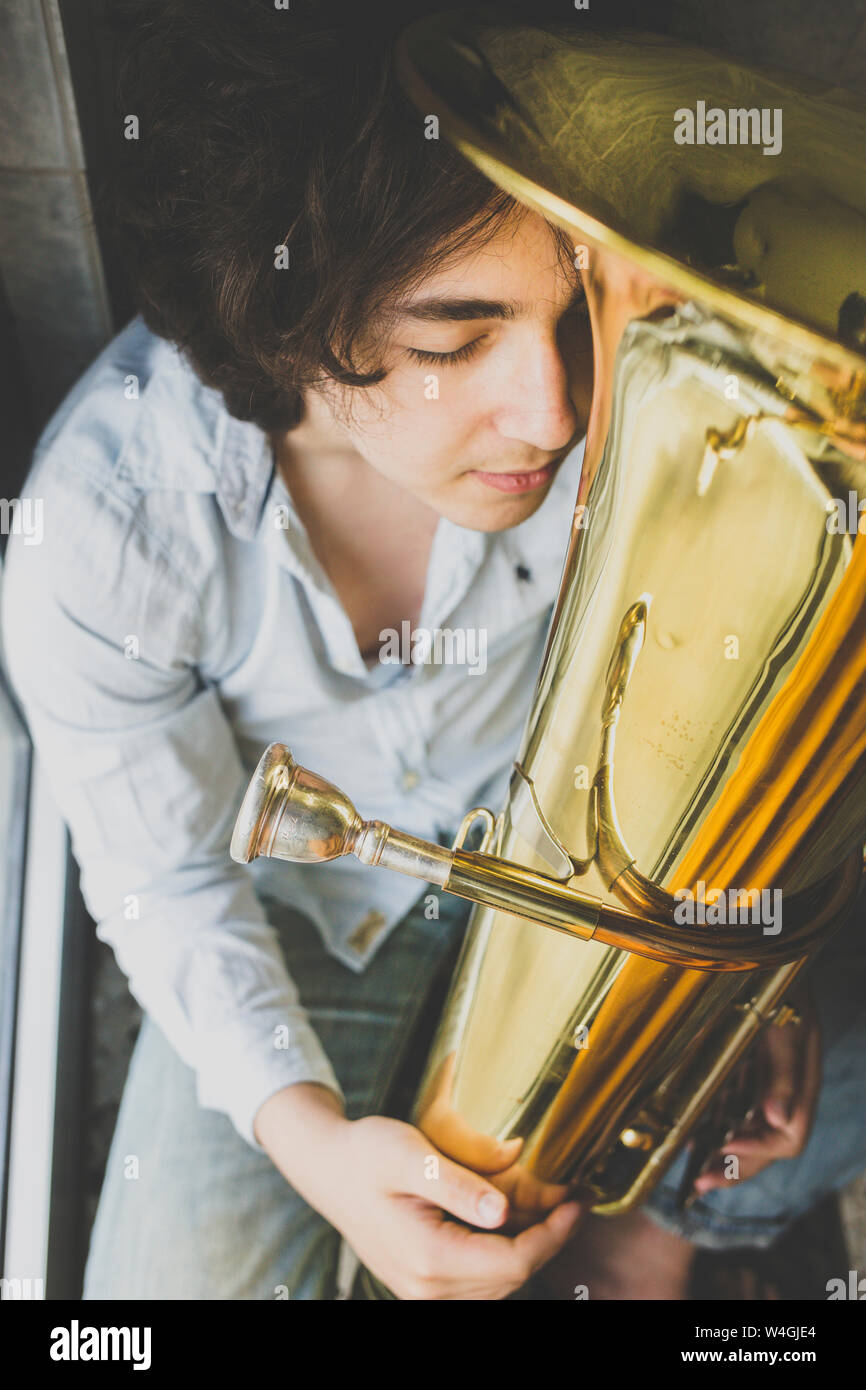 Teenage boy with eyes closed holding his tuba Stock Photo - Alamy