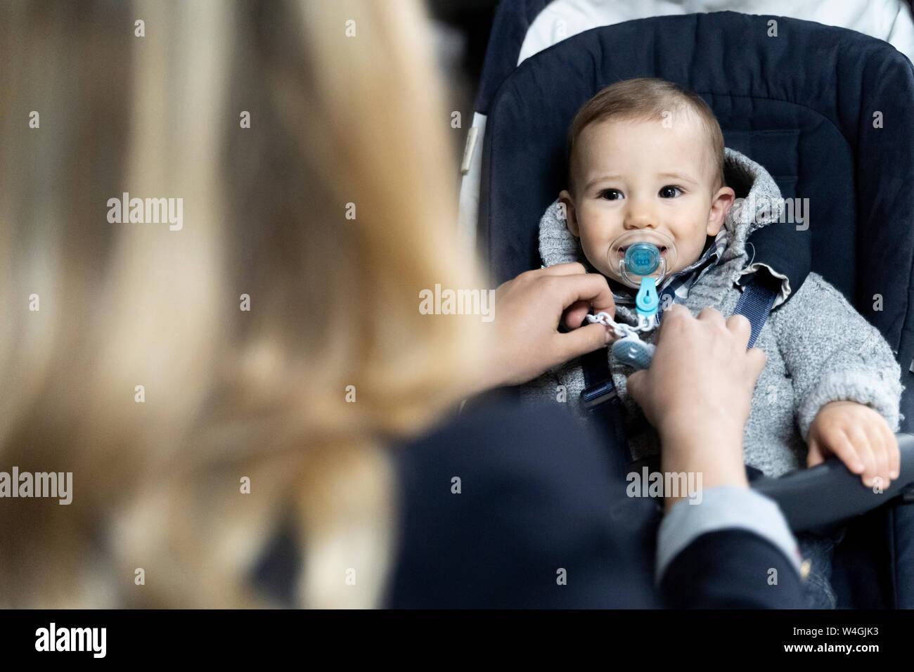 Portrait of baby boy with pacifier in strollerwatching his mother Stock ...