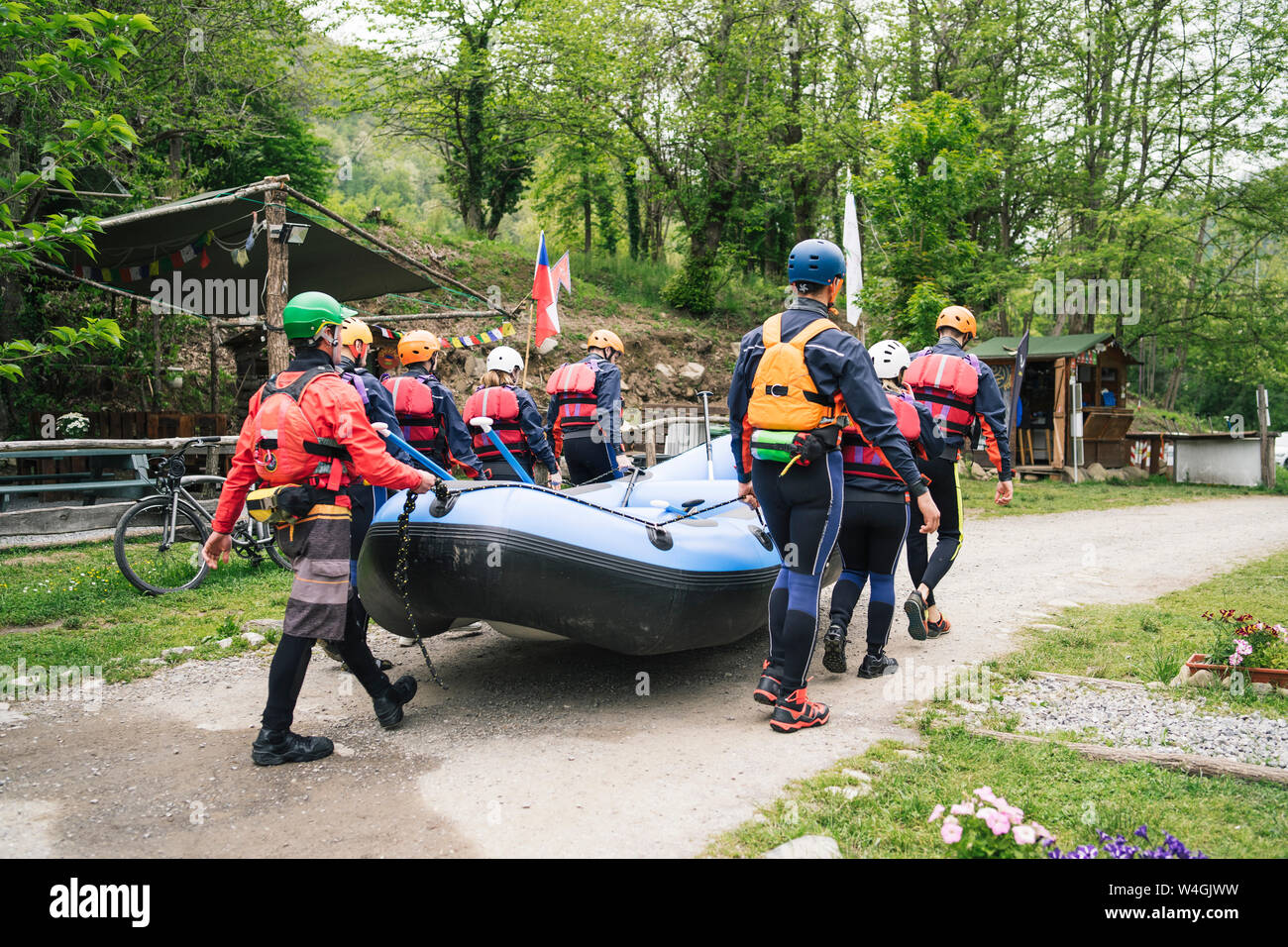 Group of friends preparing for a rafting trip carrying rubber dinghy ...