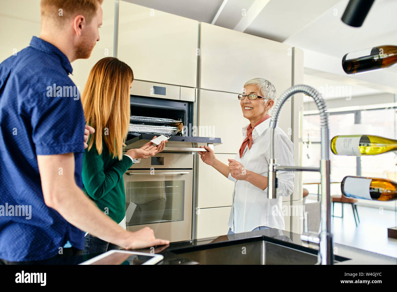 Shop assistant explaining oven to couple shopping for a new kitchen in ...