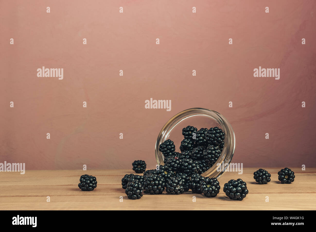 Fresh blackberry in glass bowl on a brown wooden table and dark-red ...