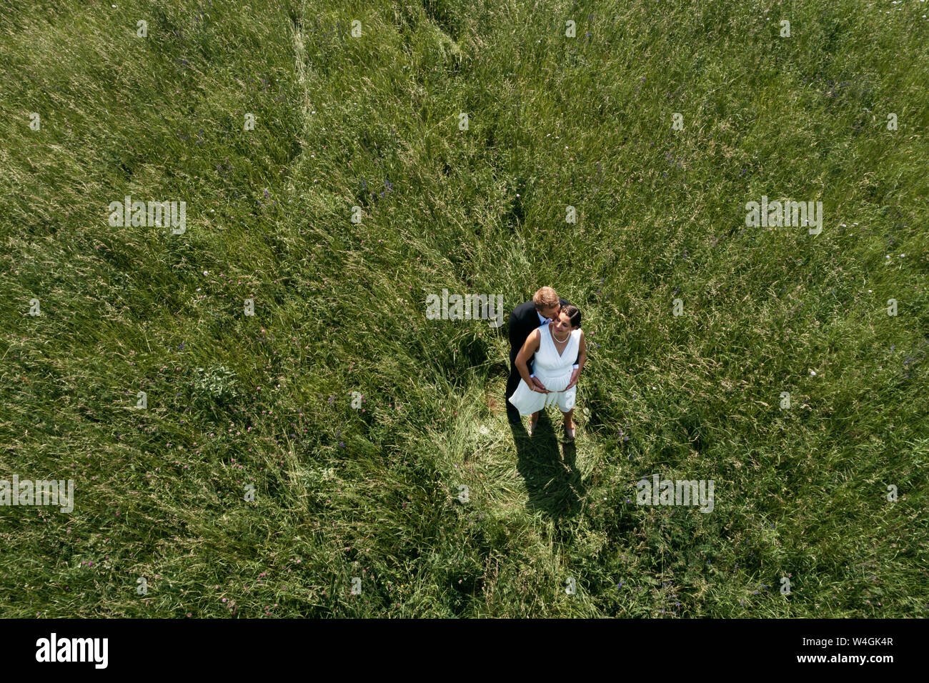 Aerial view of pregnant bride with her husband on a meadow Stock Photo ...
