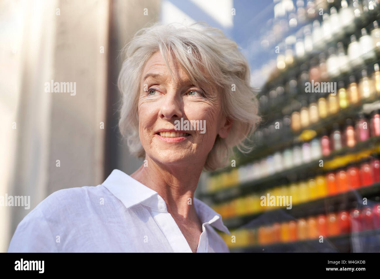 Portrait of smiling mature woman in front of window display Stock Photo ...