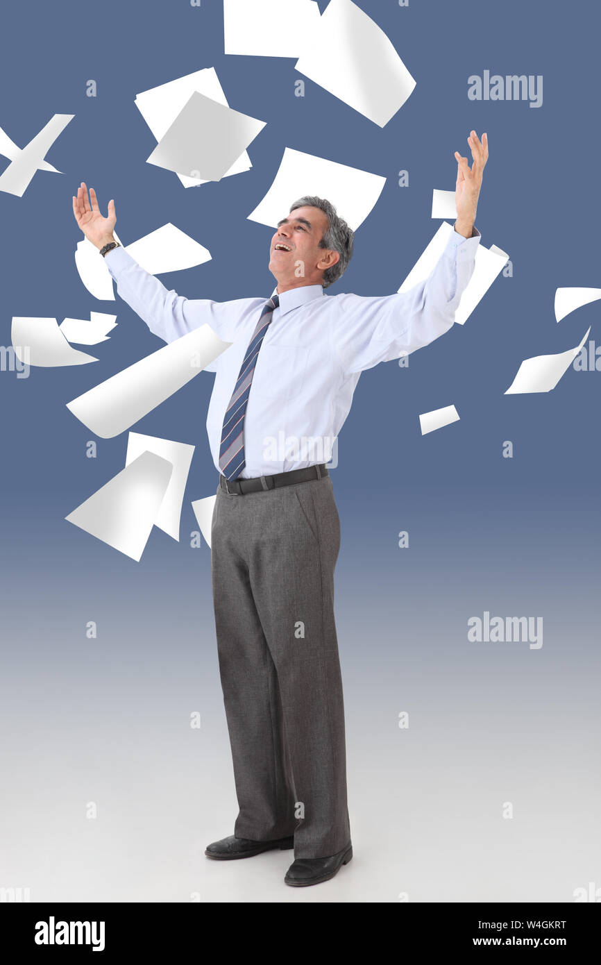 Papers falling on a businessman standing with his arms outstretched ...