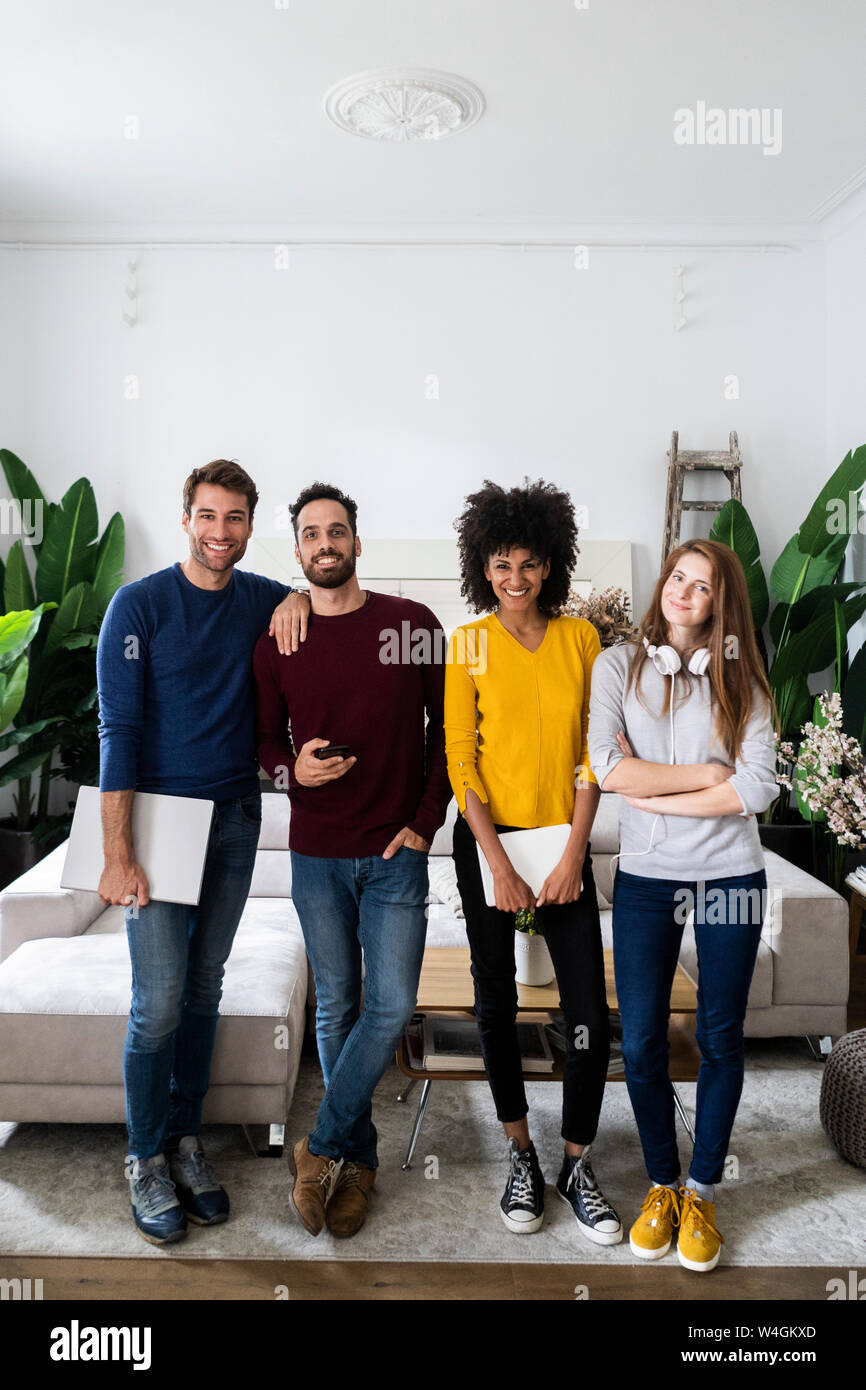 Portrait of four happy friends standing side by side in living room ...