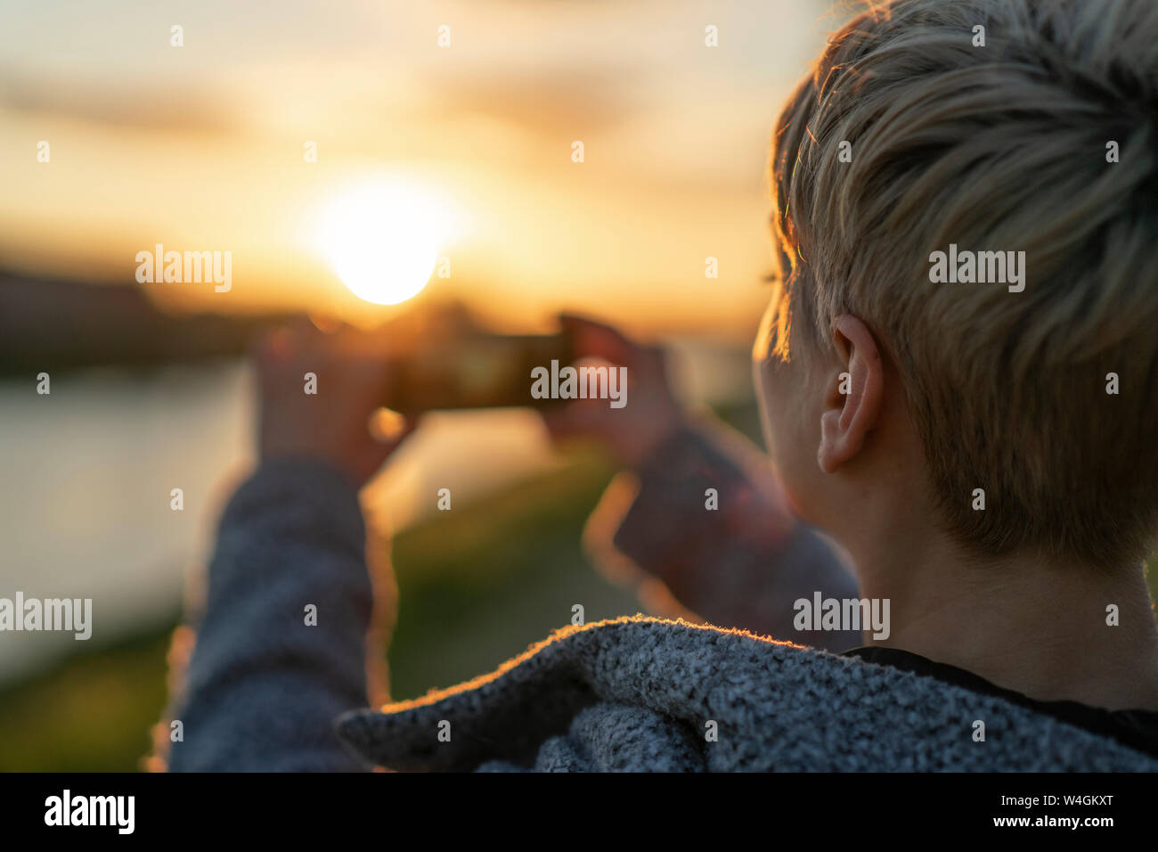 Back view of woman taking photo of sunset, close-up Stock Photo - Alamy