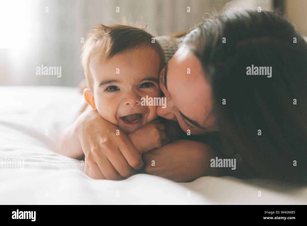 Mother and baby cuddling in bed at home Stock Photo - Alamy