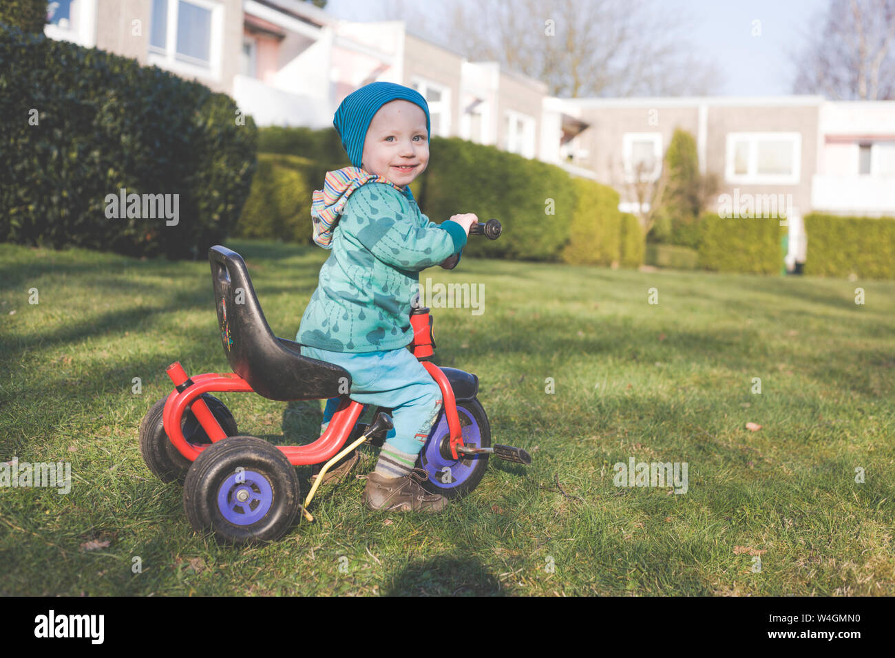 Portrait of happy little boy with tricycle on lawn Stock Photo - Alamy