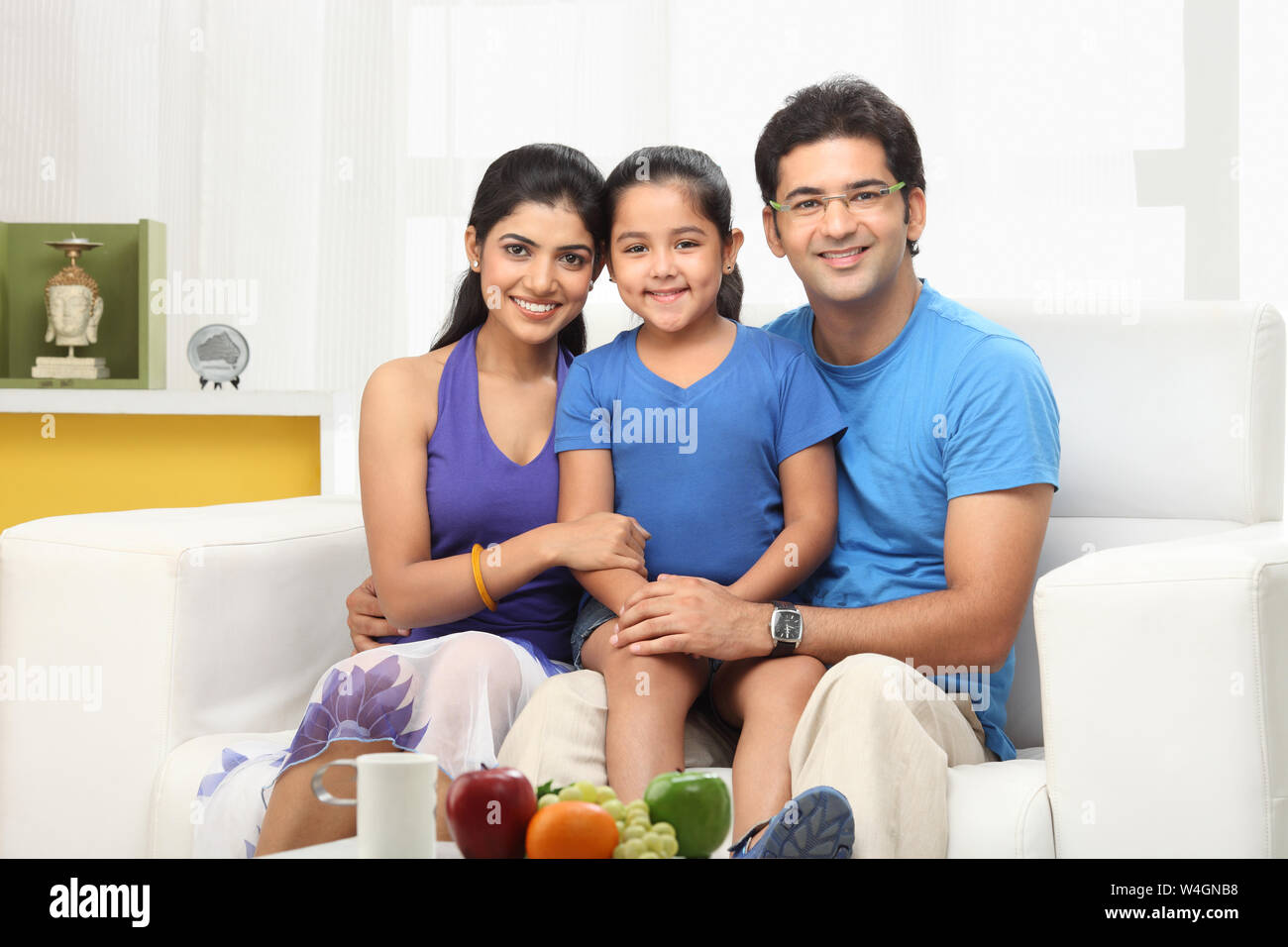 Family sitting on a couch at home Stock Photo - Alamy