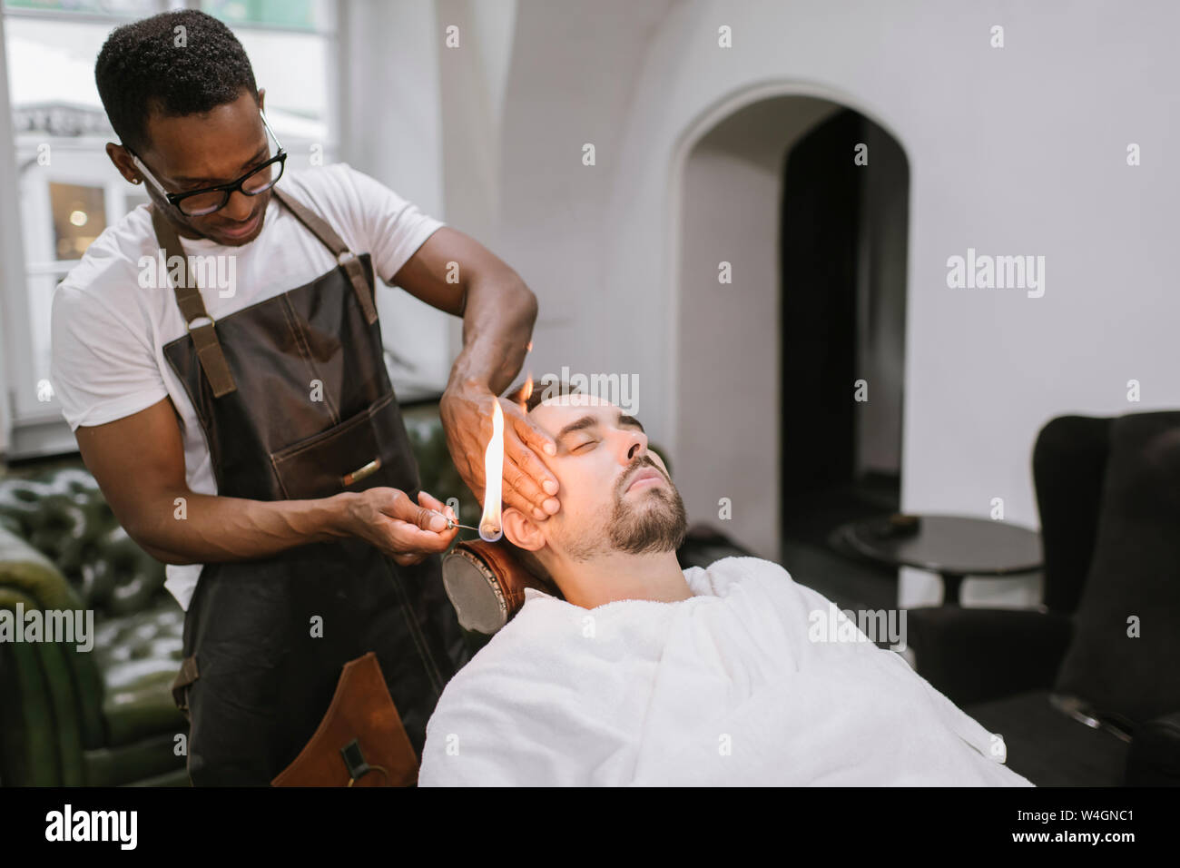 Barber removing ear hair of a customer with fire in barber shop Stock ...