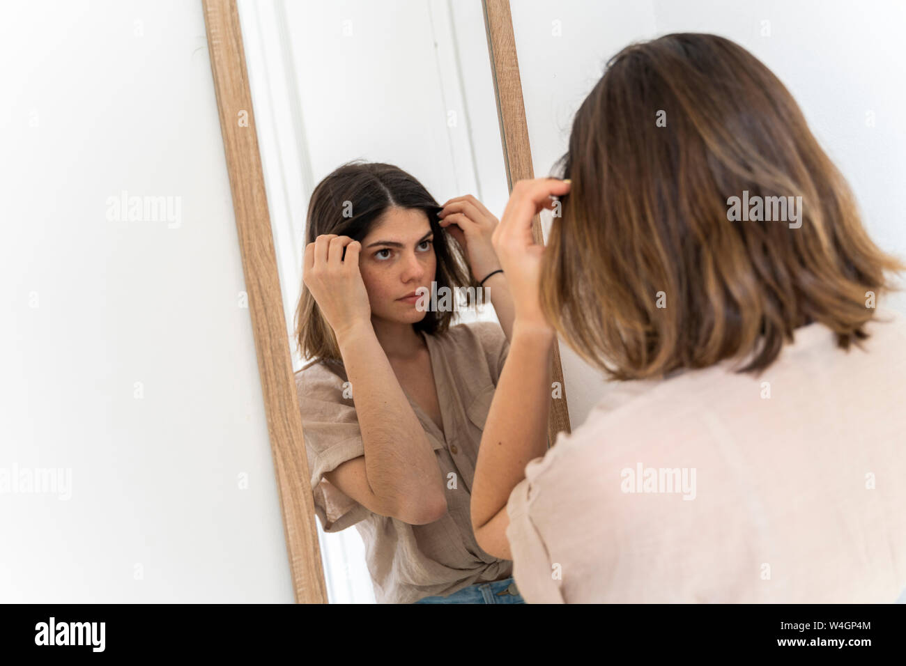 Brunette young woman looking in mirror Stock Photo - Alamy